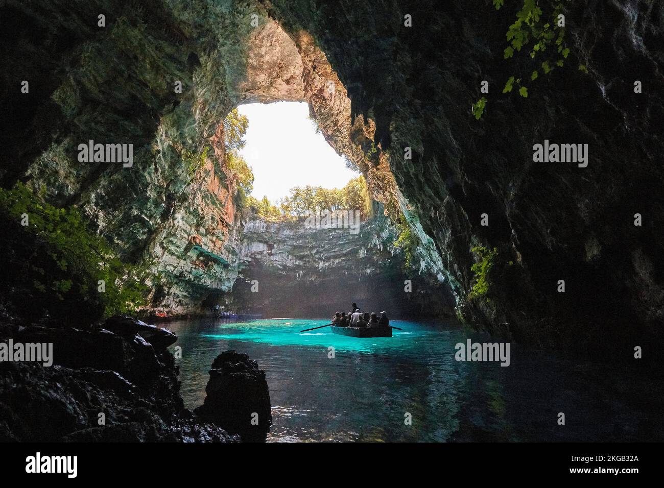 Boat with tourists, opening in cave ceiling, bright daylight, Melissani ...