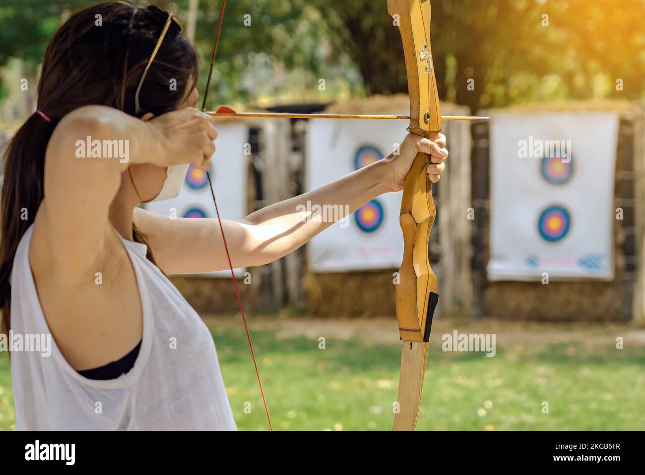 Hands of woman aims archery bow and arrow to colorful target in ...