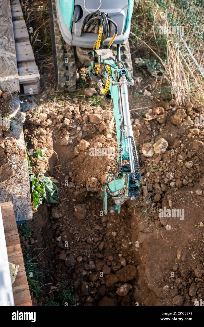 Mini excavator digs a trench to lay pipes. Close up of an excavator ...
