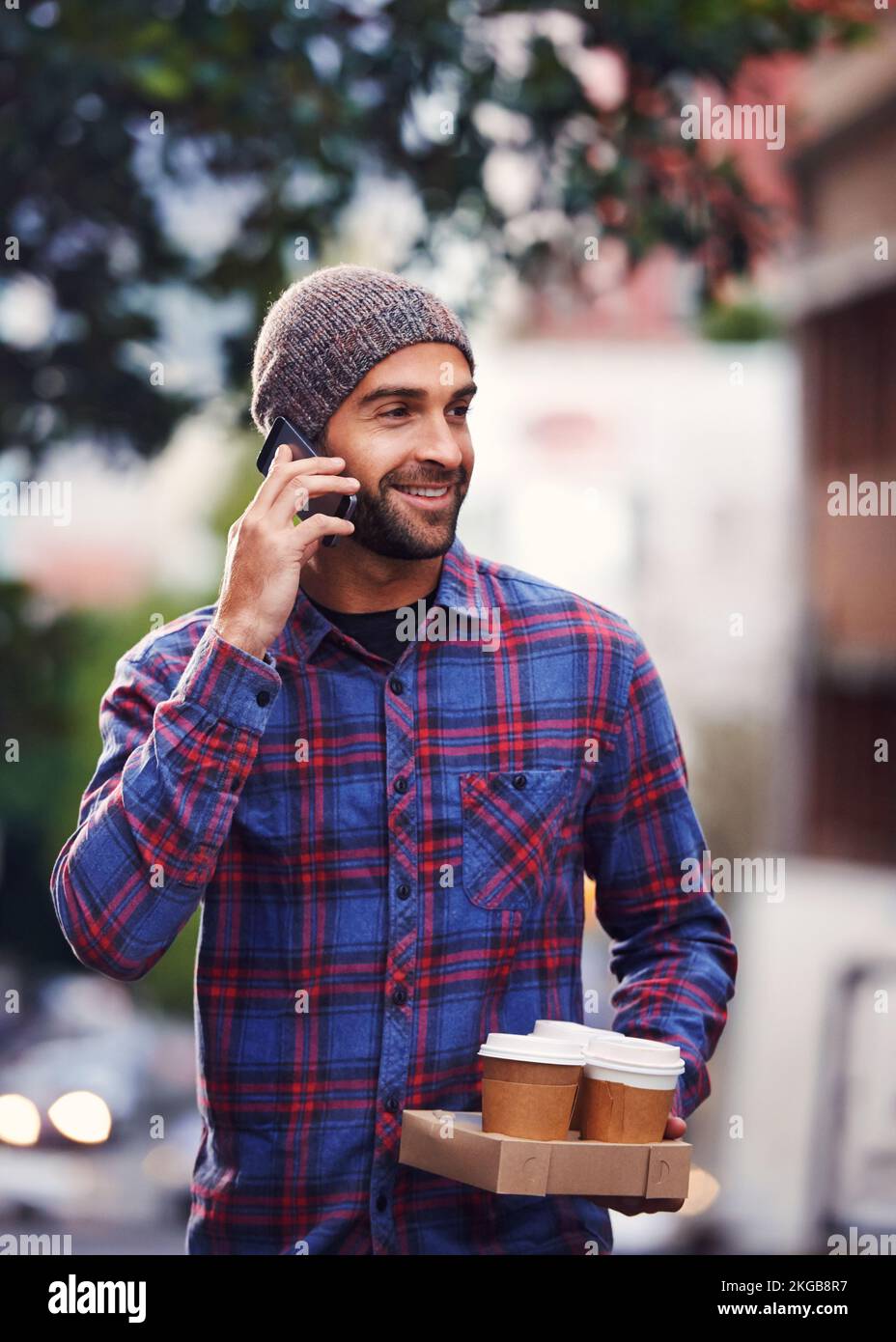 Im bringing coffee. a handsome young man in winter wear talking on his ...