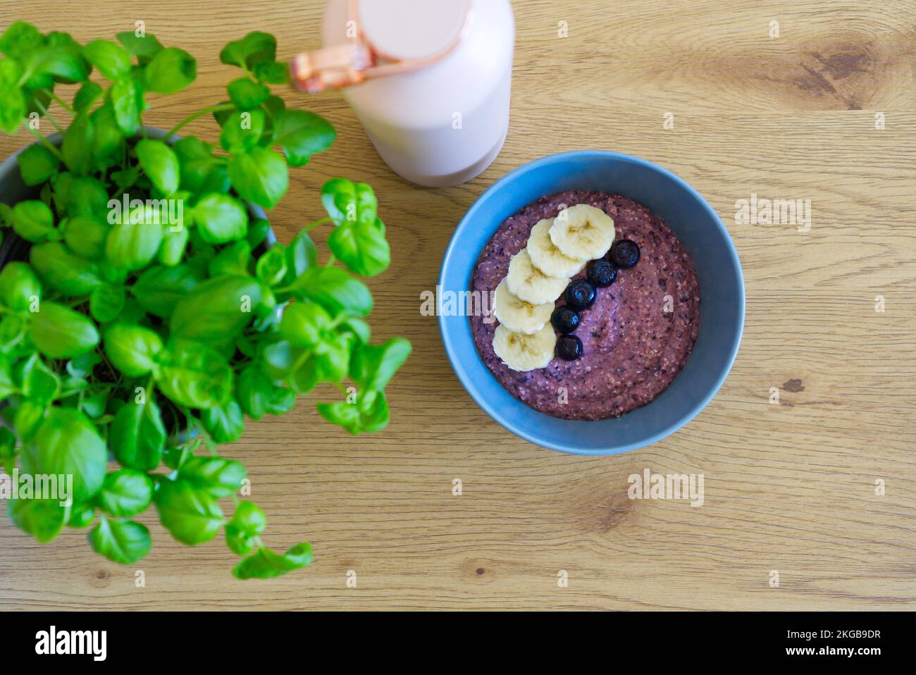 A top view of a blueberry smoothie, a basil herb and a bottle on the ...