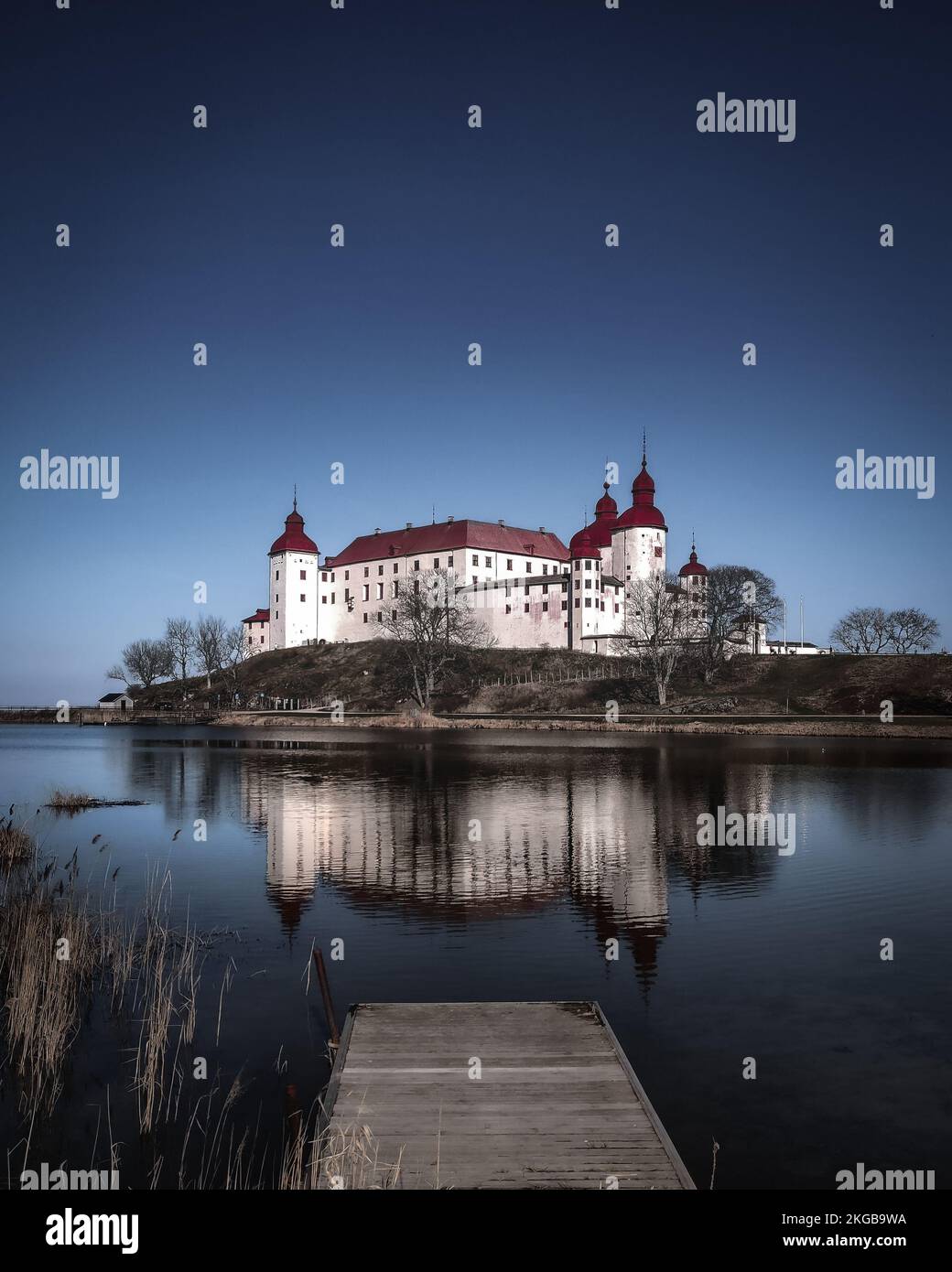 A vertical shot of medieval Lacko Castle reflecting on the still water ...