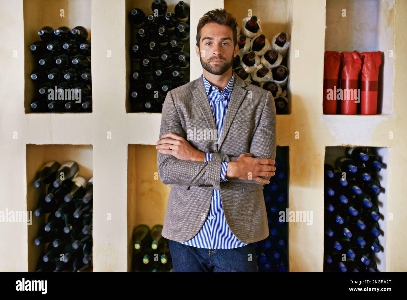 Pick your vintage. A young man standing in front of a rack full of wine ...