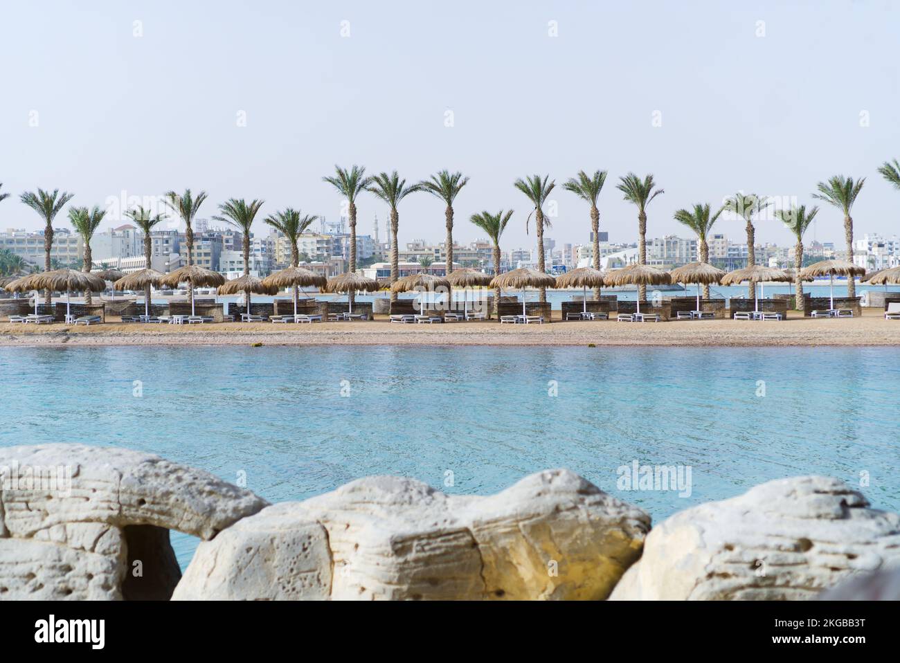A beach with bamboo umbrellas and palm trees with the city in the ...