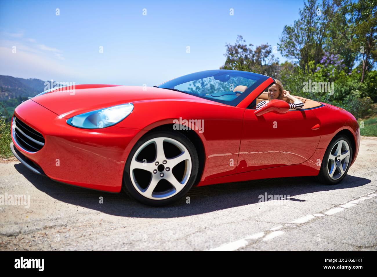 My ride makes everyone jealous. a young woman driving in a sports car ...