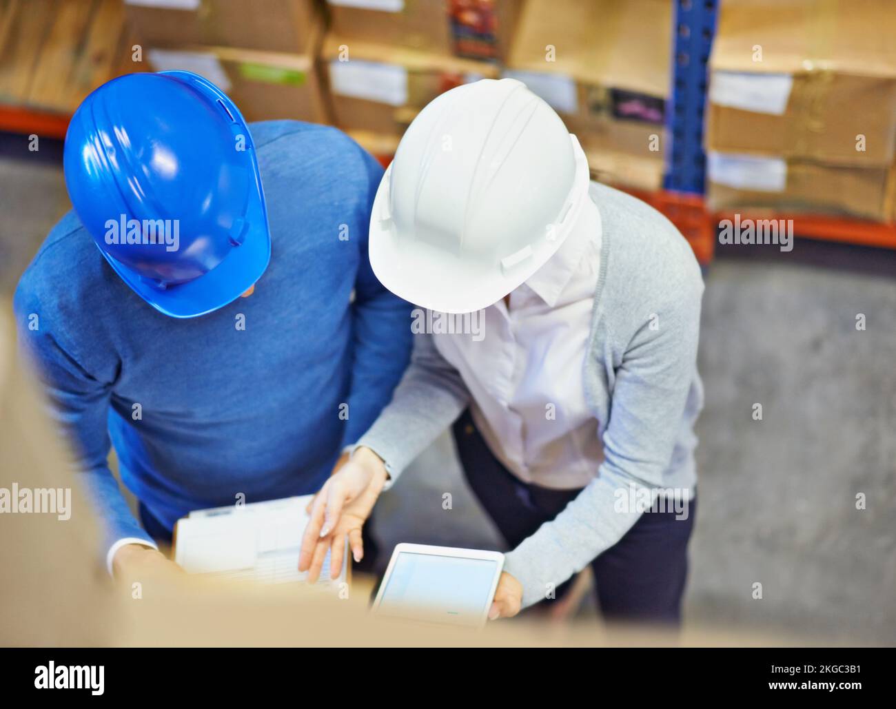 Factory managers. Overhead shot of two people wearing hardhats working ...