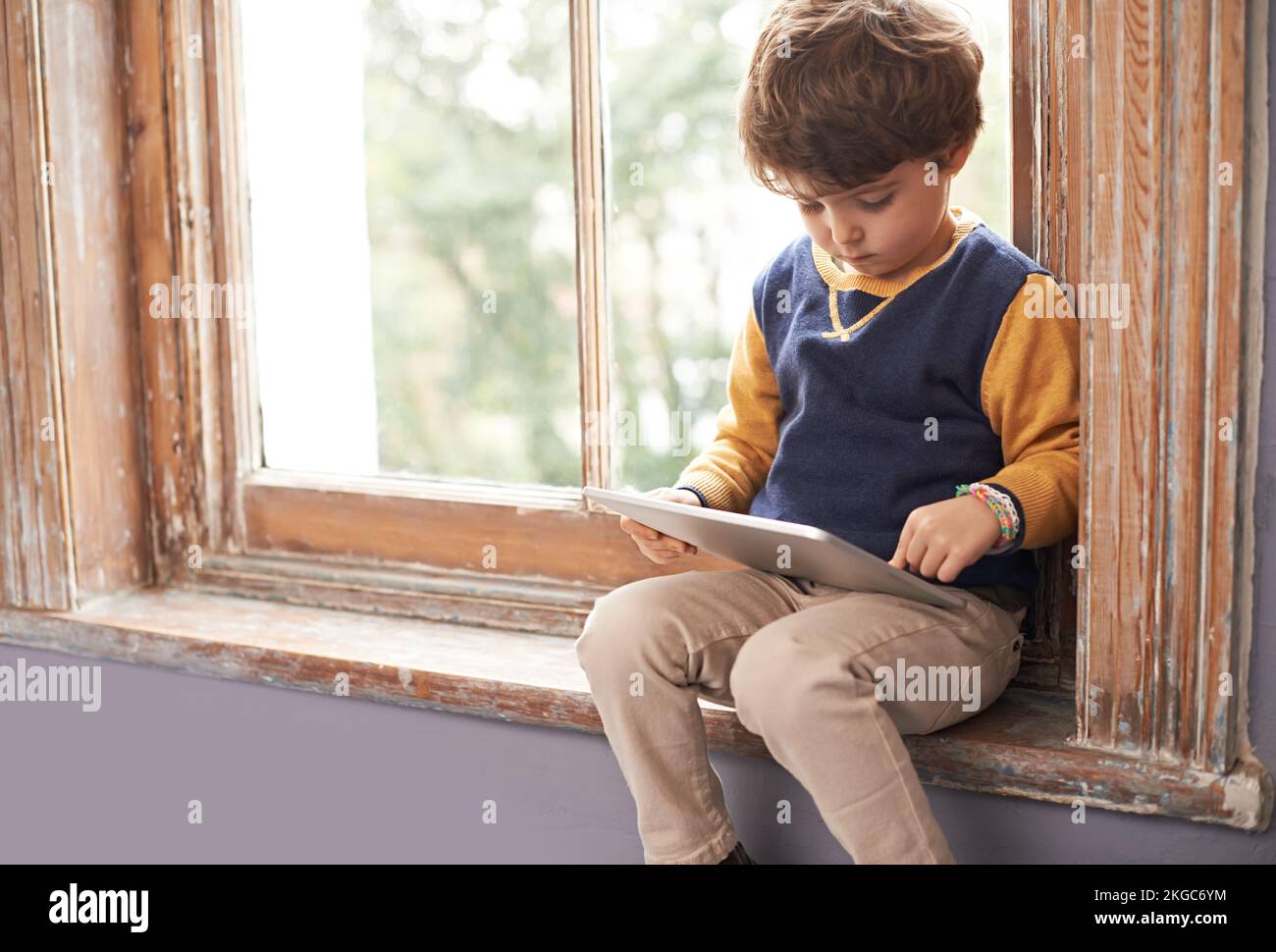 Hes tech savvy already. a cute little boy using a tablet while sitting ...