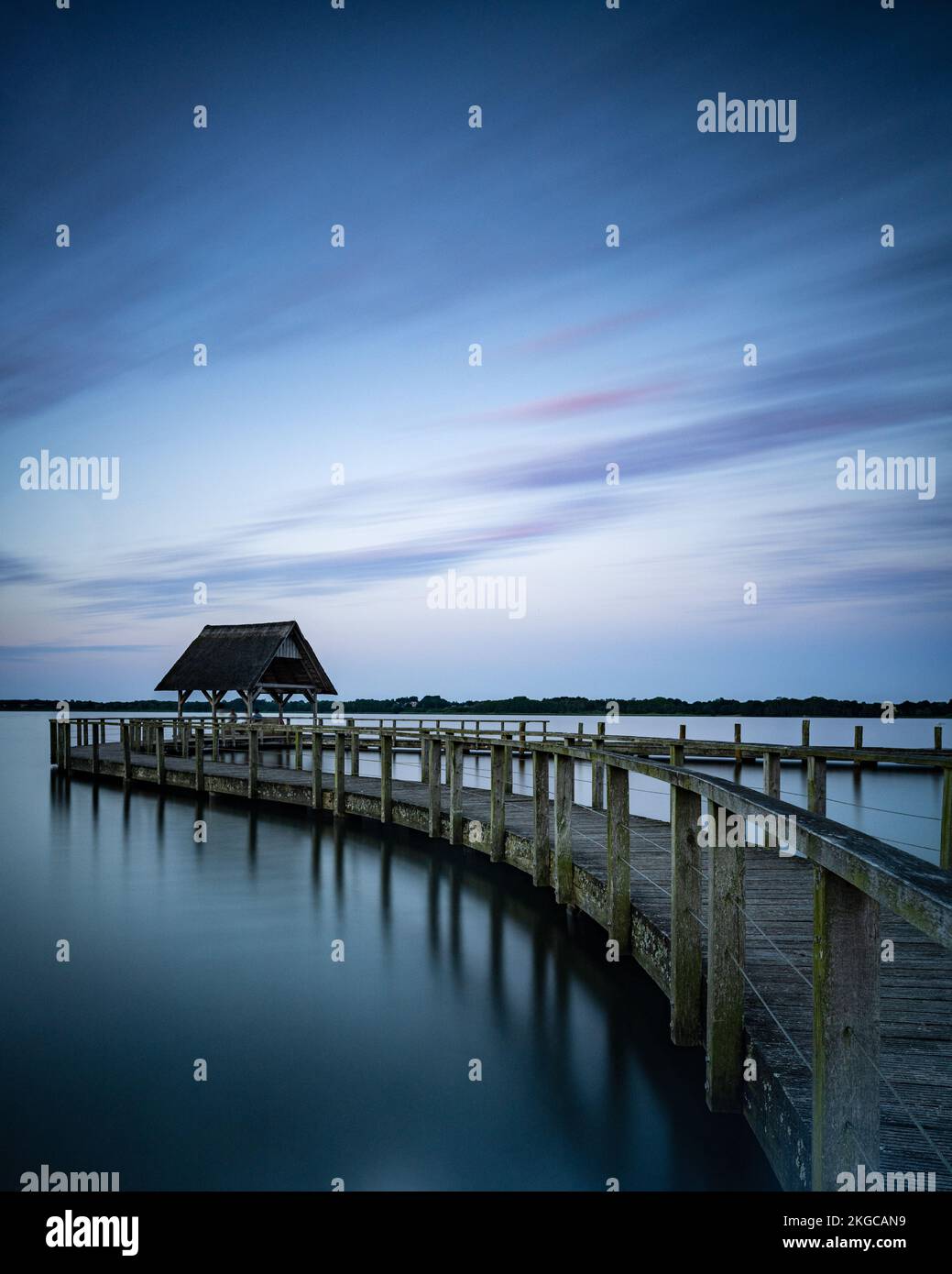 The vertical long exposure shot of a wooden pier in Hemmelsdorfer See ...