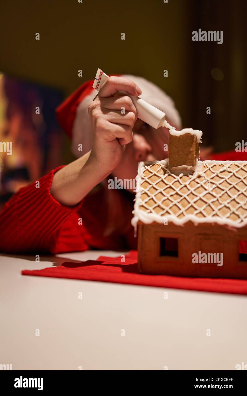 Woman in red hat building gingerbread house. Preparing to celebrate ...