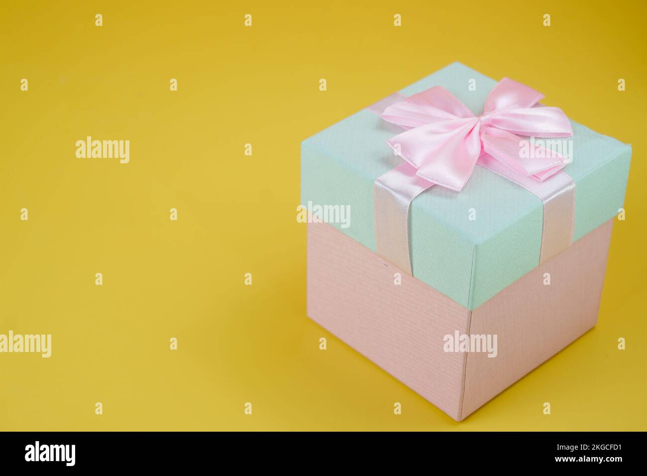 Pink and cyan gift box with ribbon bow isolated on yellow background ...