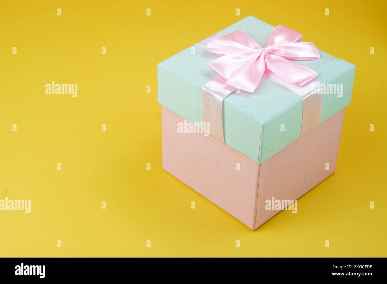 Pink and cyan gift box with ribbon bow isolated on yellow background ...