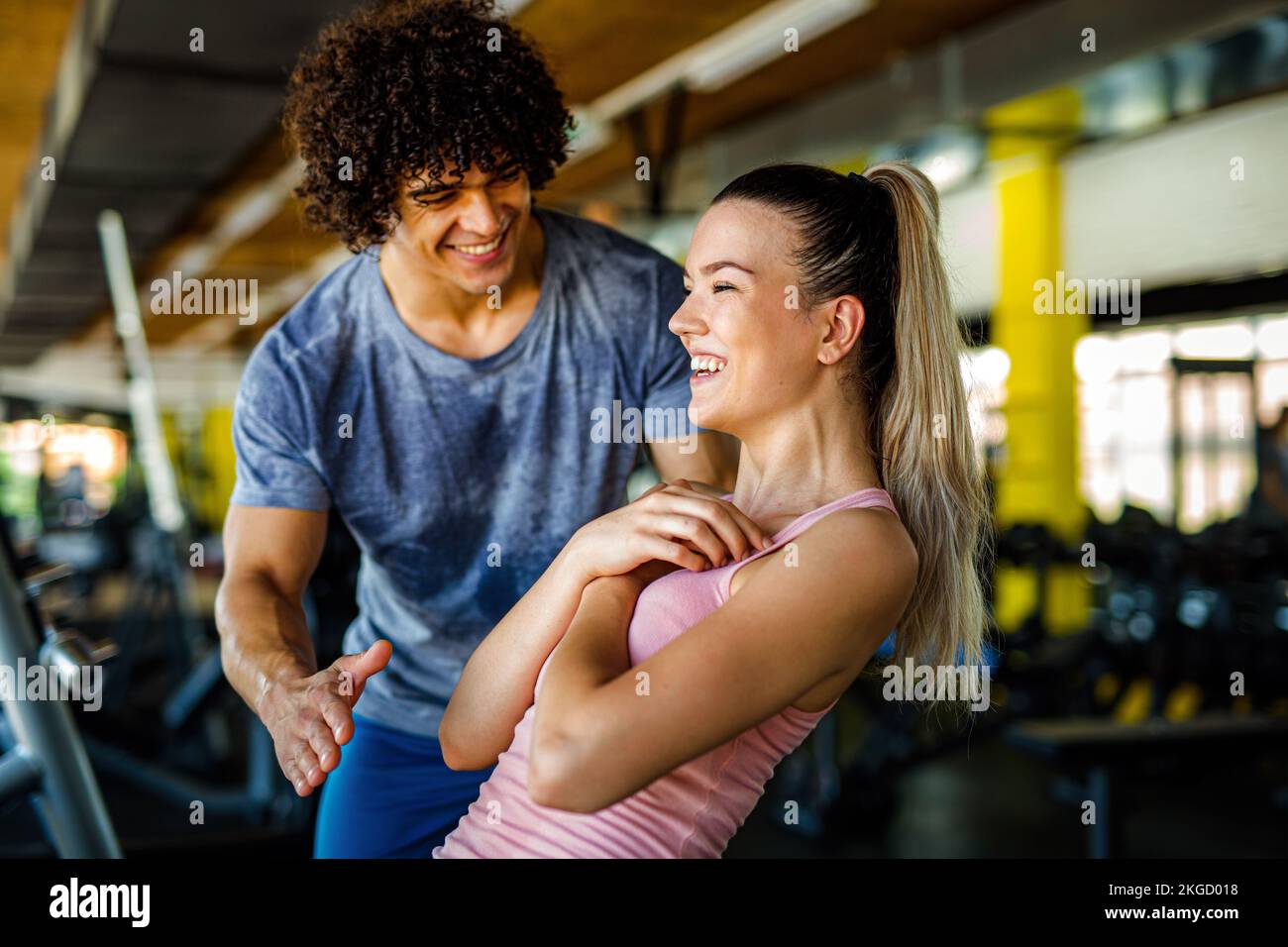 Beautiful woman doing exercises in gym with personal trainer together ...