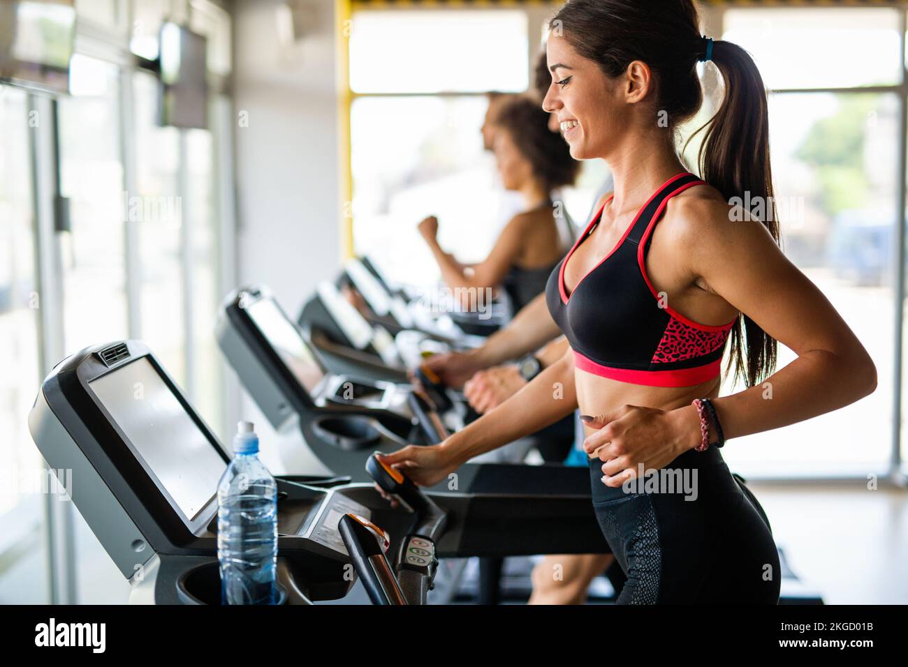 Group of fit young people running on a treadmill in health club. People ...