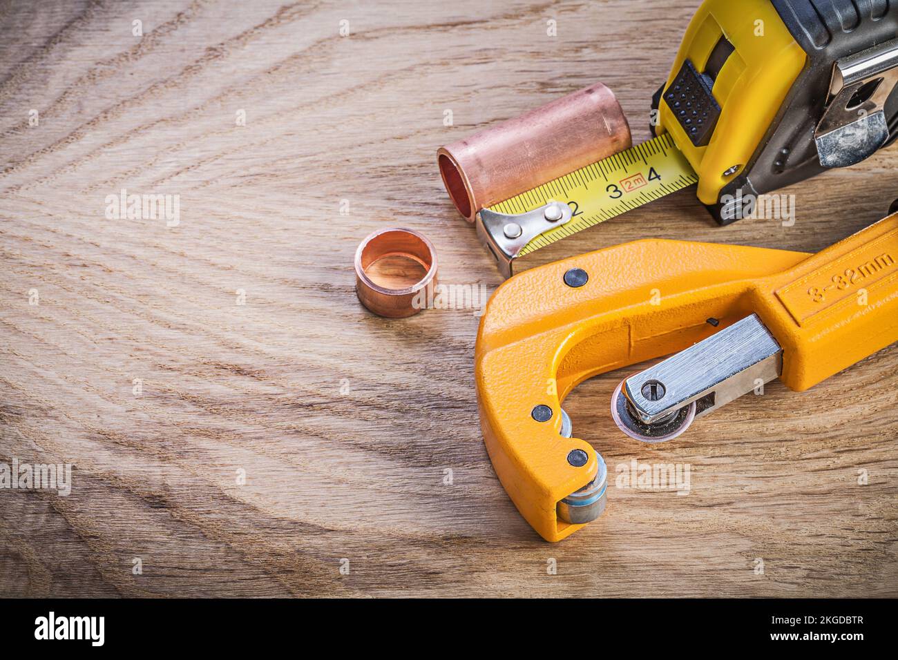 Assortment of brass water pipe cutter measuring tape on wood board ...