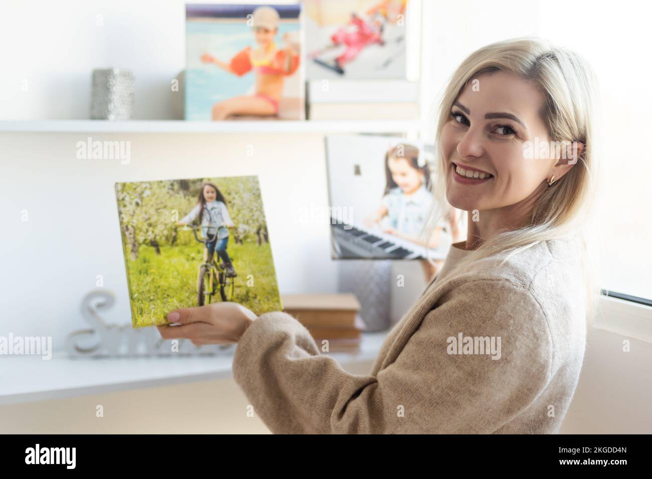 Young woman hanging a photo canvas painting on the wall Stock Photo - Alamy