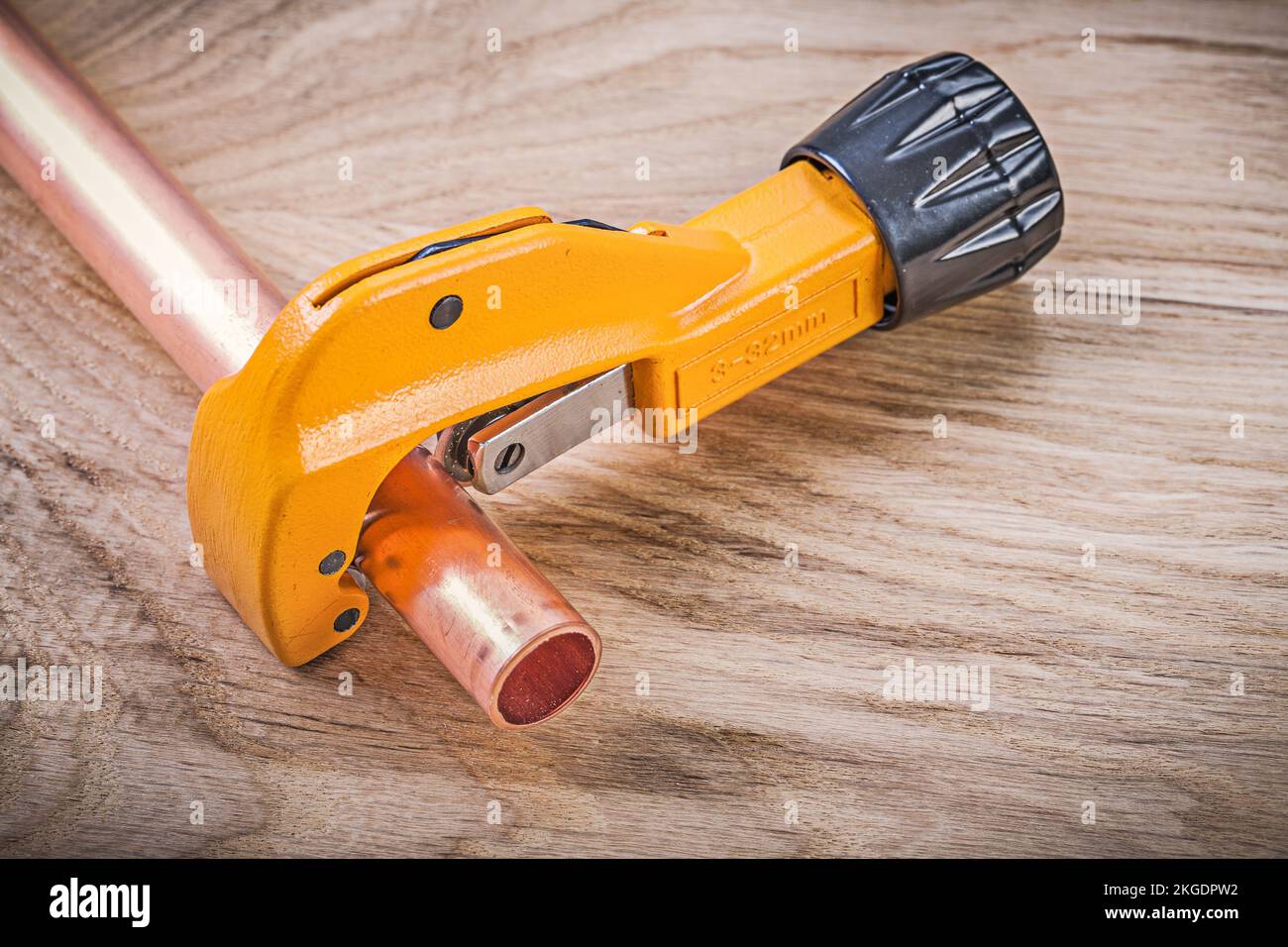 Composition of copper water pipe cutter on wooden board plumbing ...