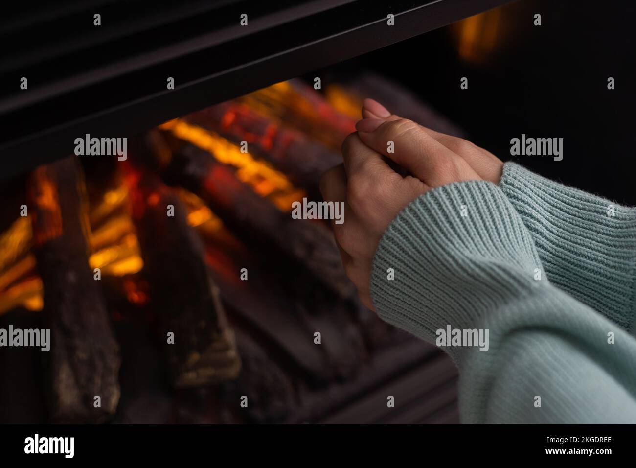 Young woman warming hands near fireplace at home. Concept of heating ...