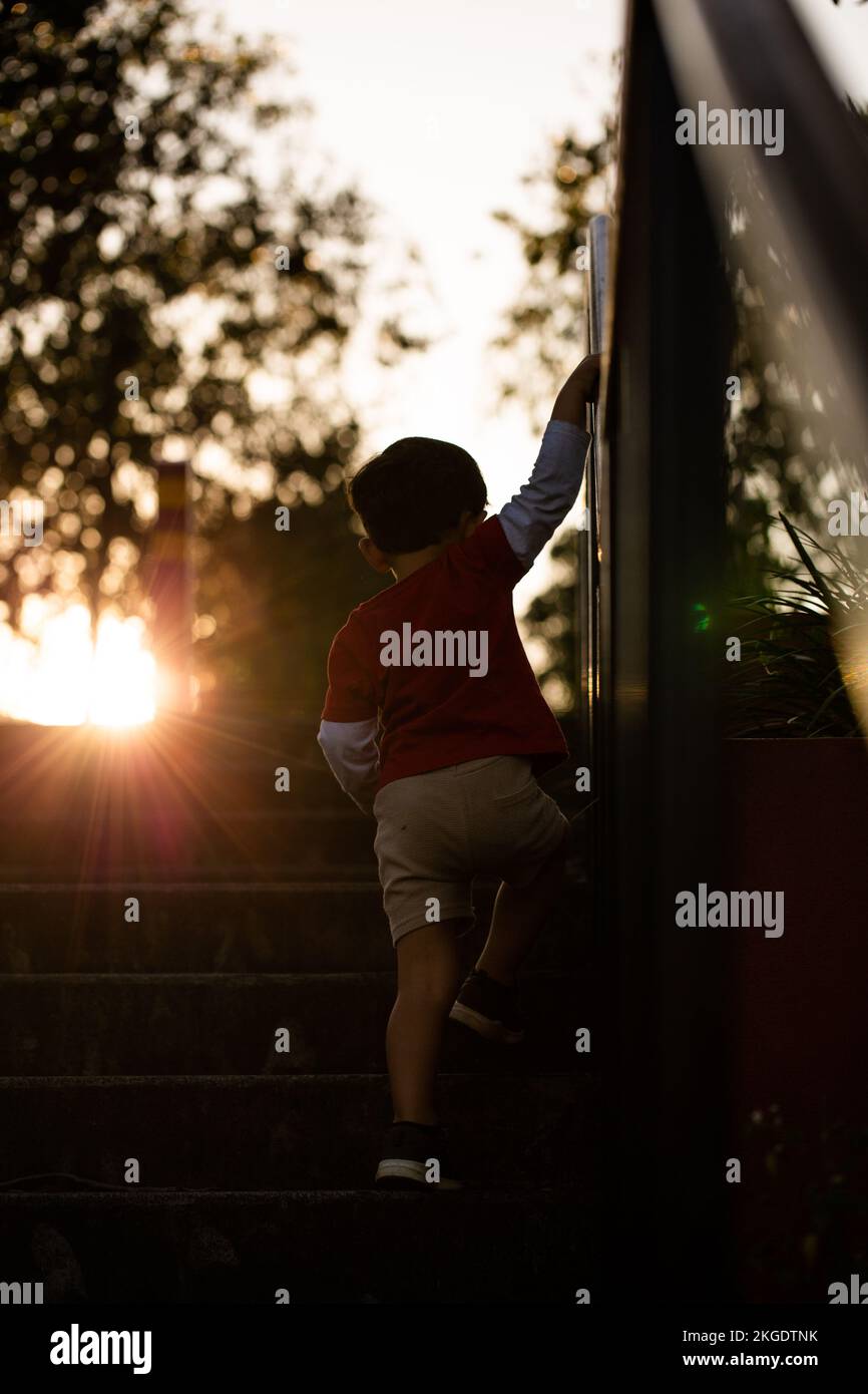 A little boy walking up the stairs on the sunset Stock Photo - Alamy