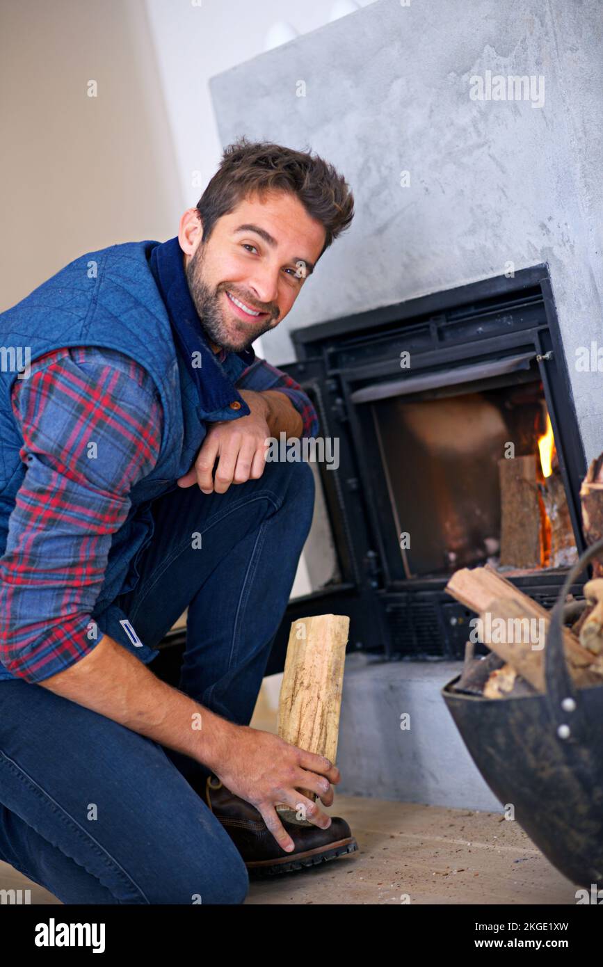 Keeping Winter at bay. a young man building a fire in his fireplace at ...