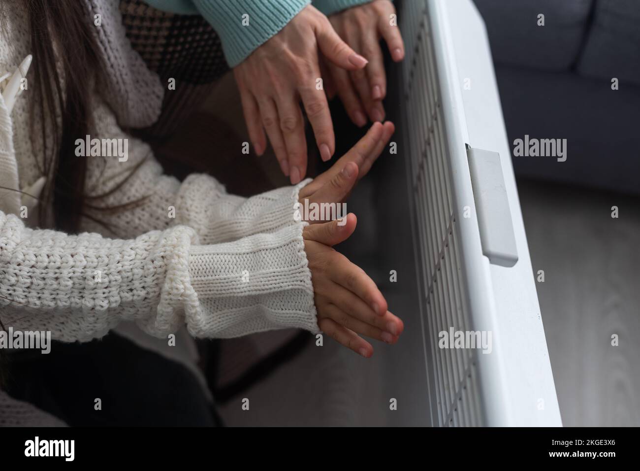 At the electric heater, people are warming themselves, covered with a ...