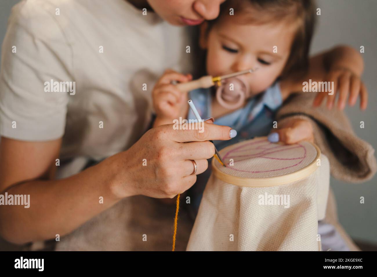 Close-up portrait of a mother sitting with needles with her little ...