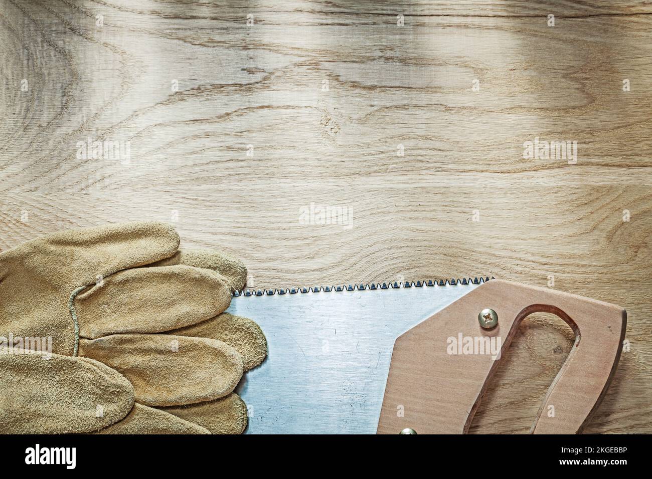 Leather protective gloves stainless handsaw on wooden board ...