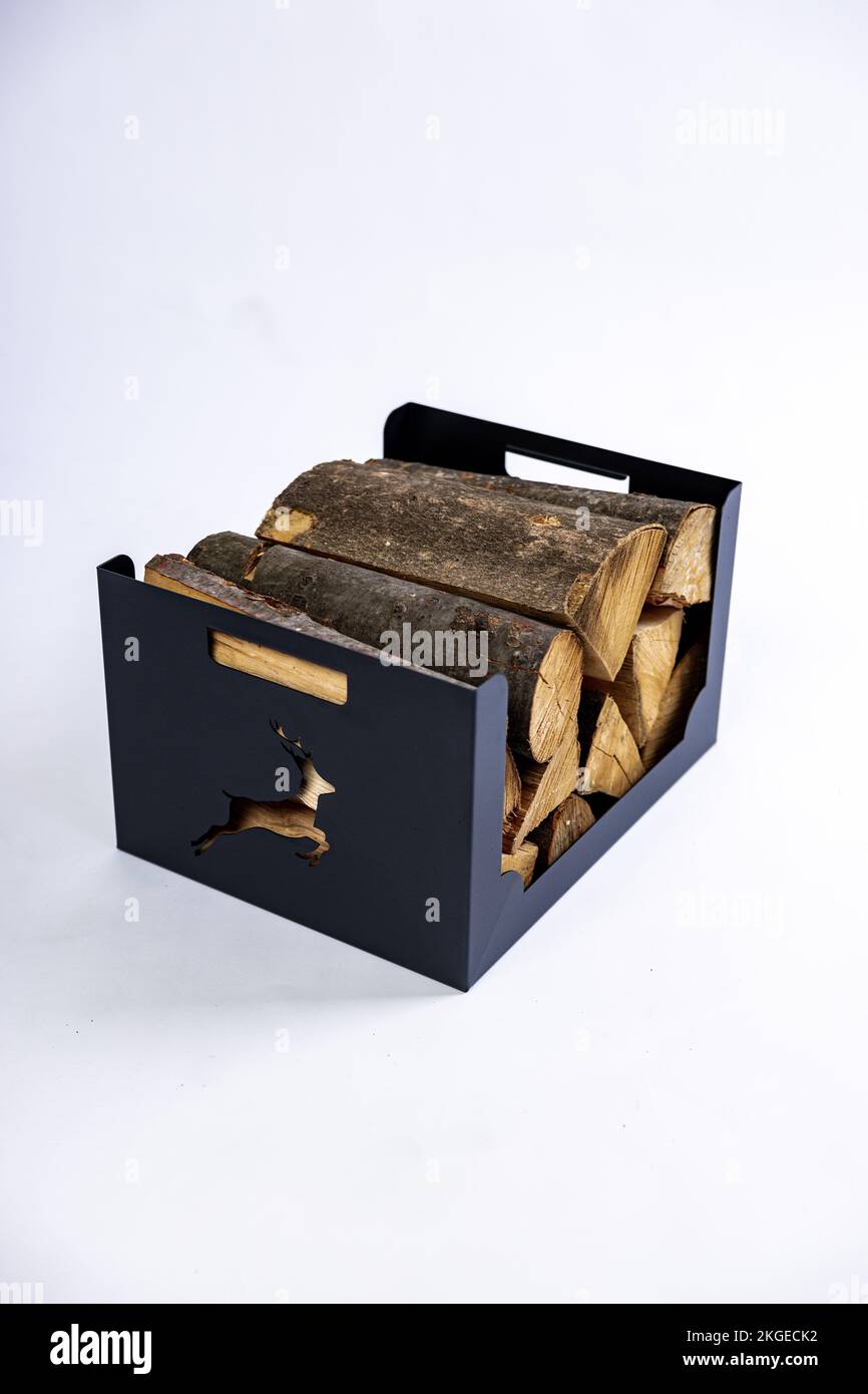 A metal box for firewood with wood logs in it on white background in a ...