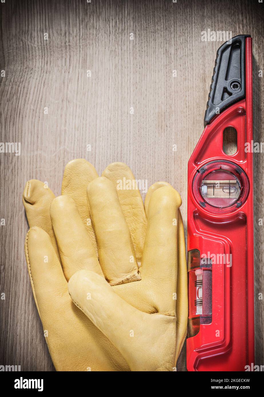 Leather working gloves red construction level on wooden board vertical ...