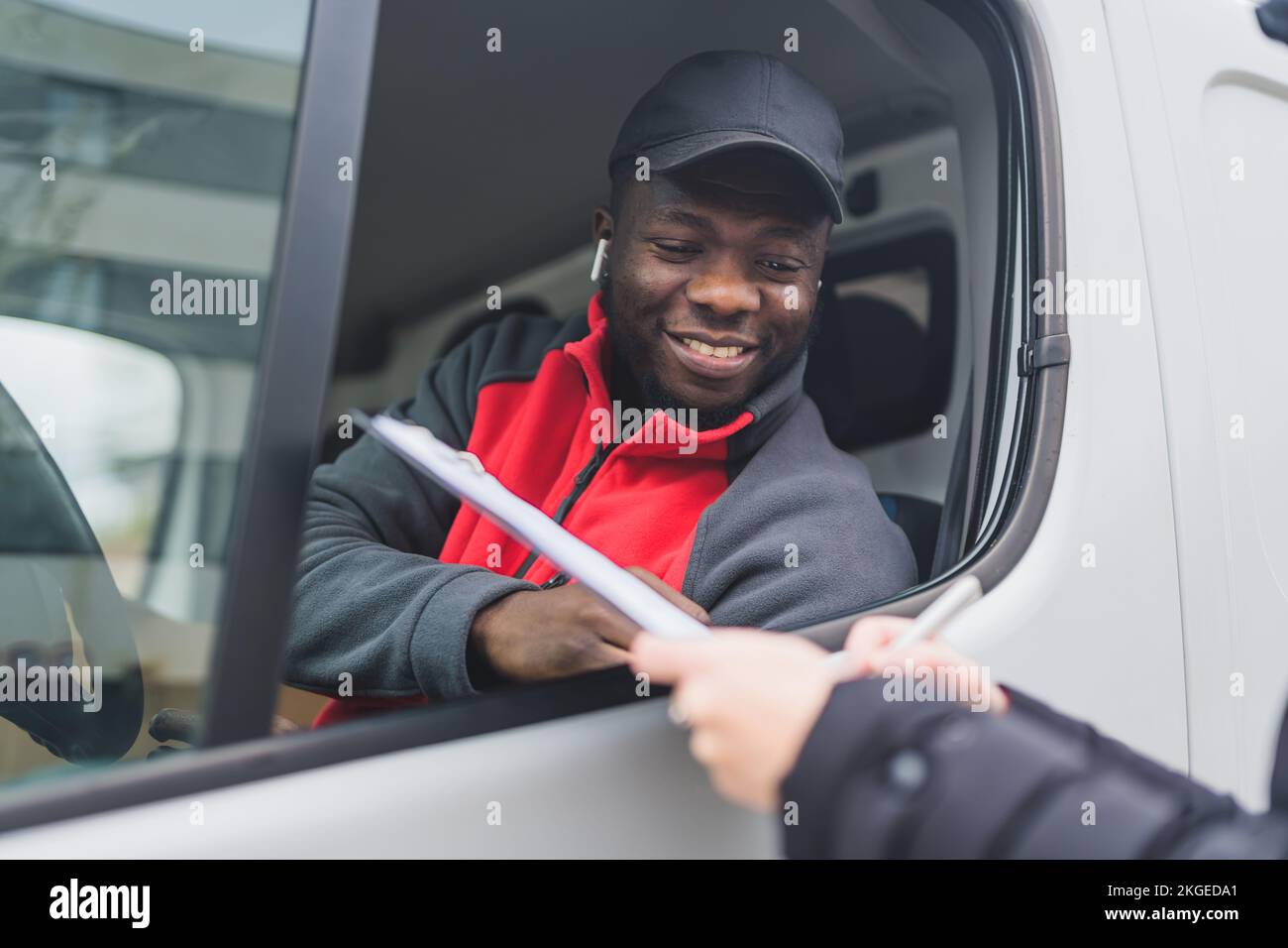 Black young adult delivery man sitting inside white van smiling looking ...