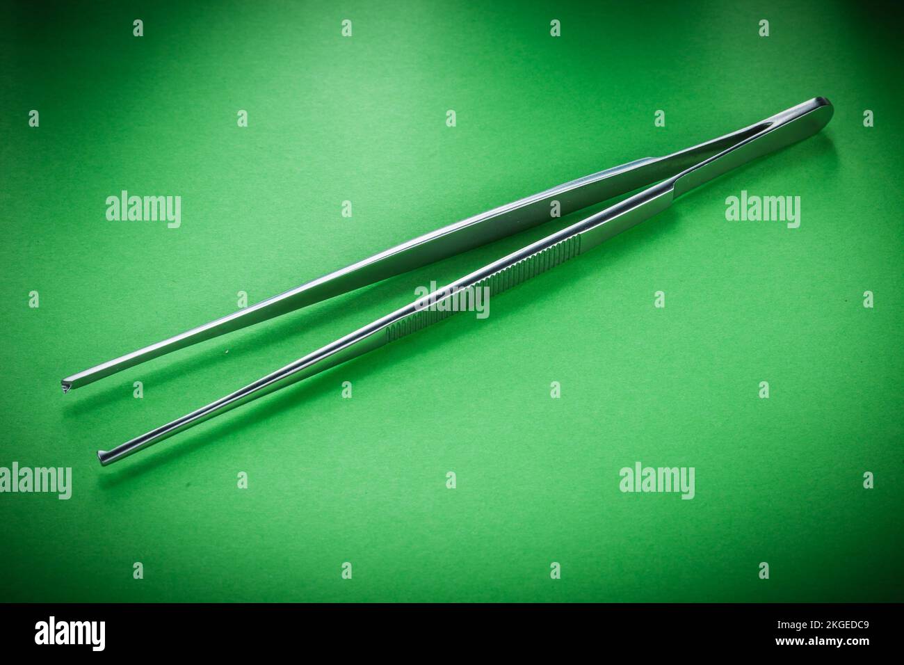 Medical tweezers on green background medicine concept Stock Photo - Alamy