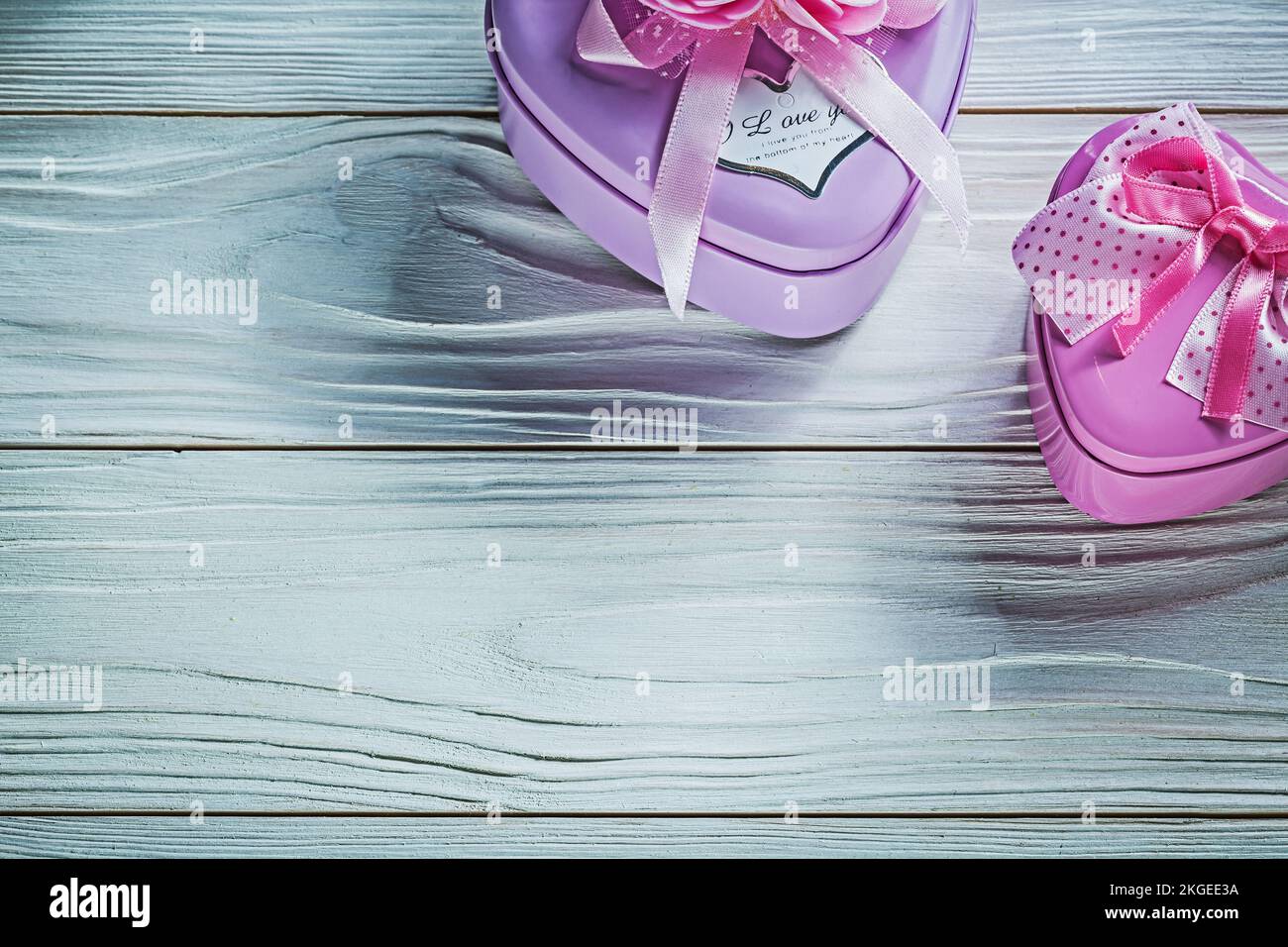 Metal heart-shaped small present boxes with pink ribbons on wooden ...