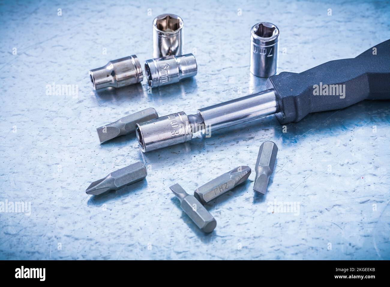 Metallic background with black screwdriver and set of steel screw bits ...