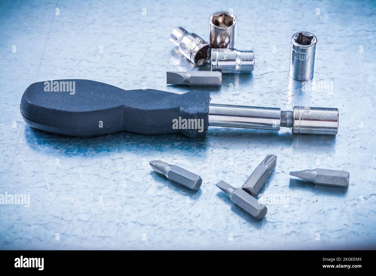 Metallic background with reversible screwdriver and set of steel screw ...