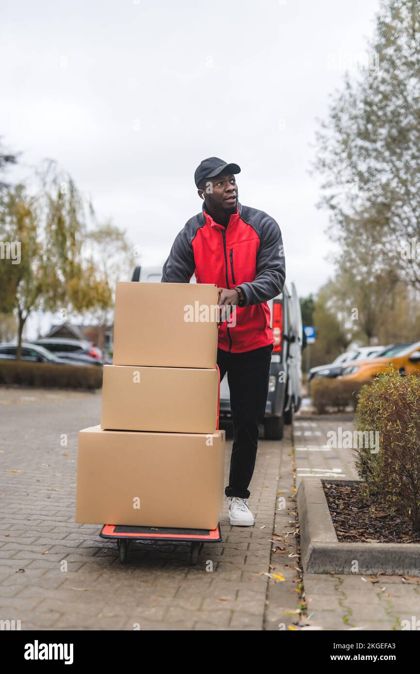 Black young adult delivery man wearing red pullover and black cap ...