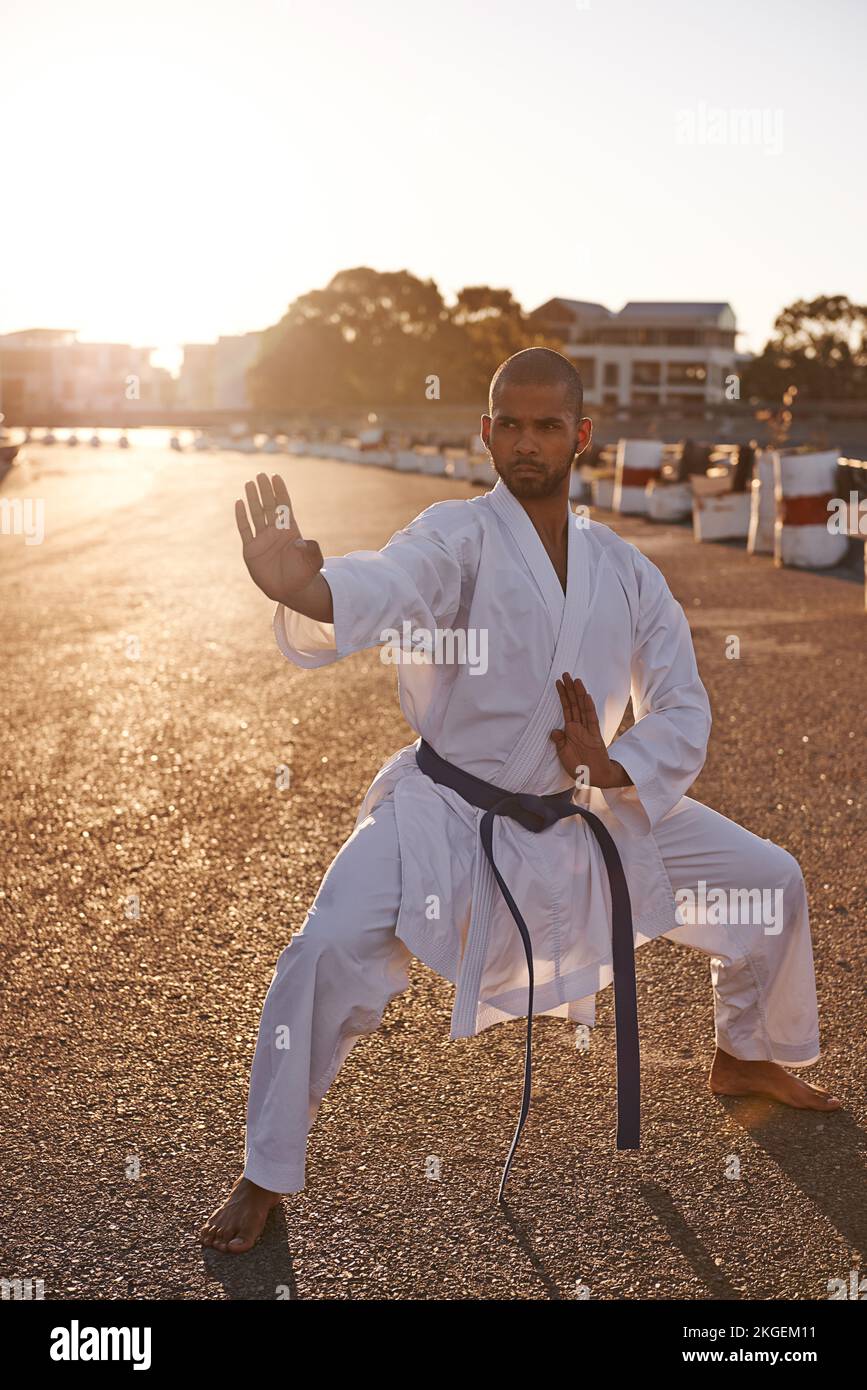Completing his kata. A young karate professional practicing while ...