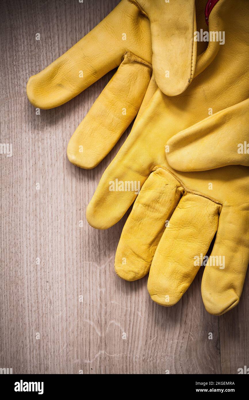 Pair of yellow leather protective gloves on wooden background ...