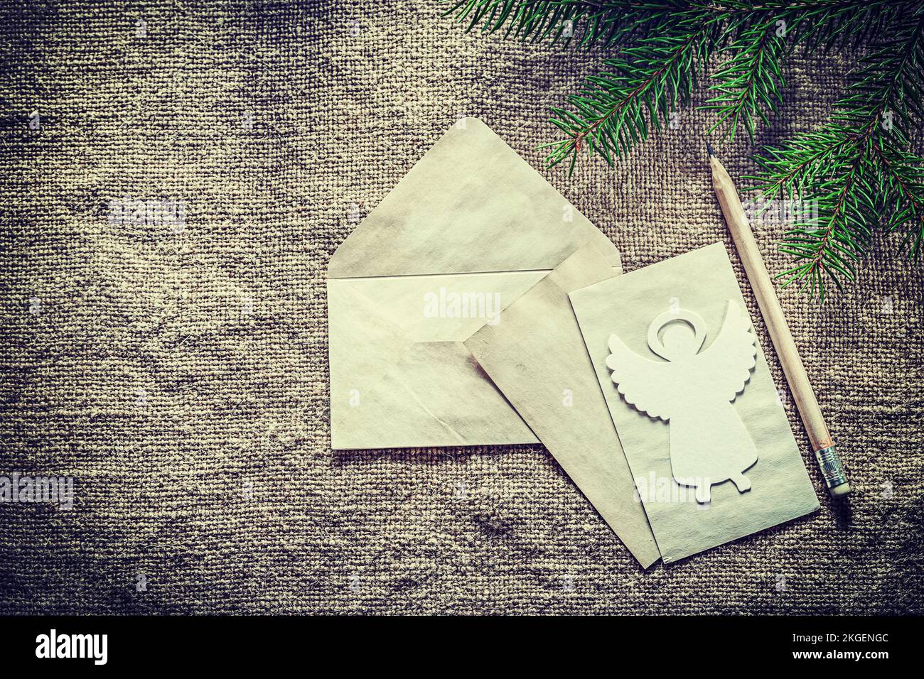 Pine tree branch envelope paper pencil angel on sacking background ...