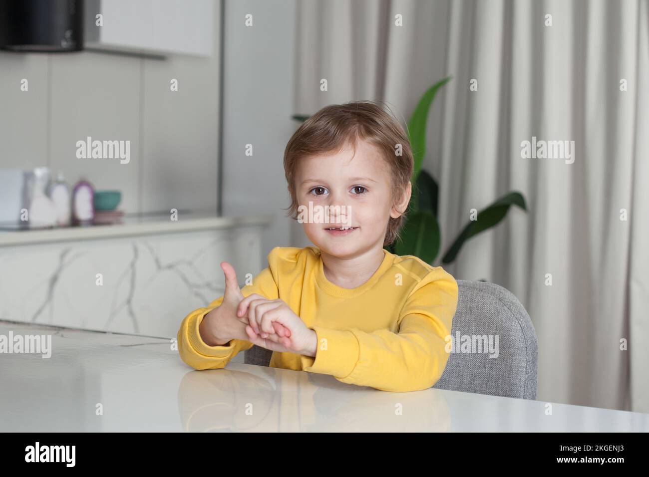 Portrait of adorable cute child boy in yellow sweater sitting on white ...