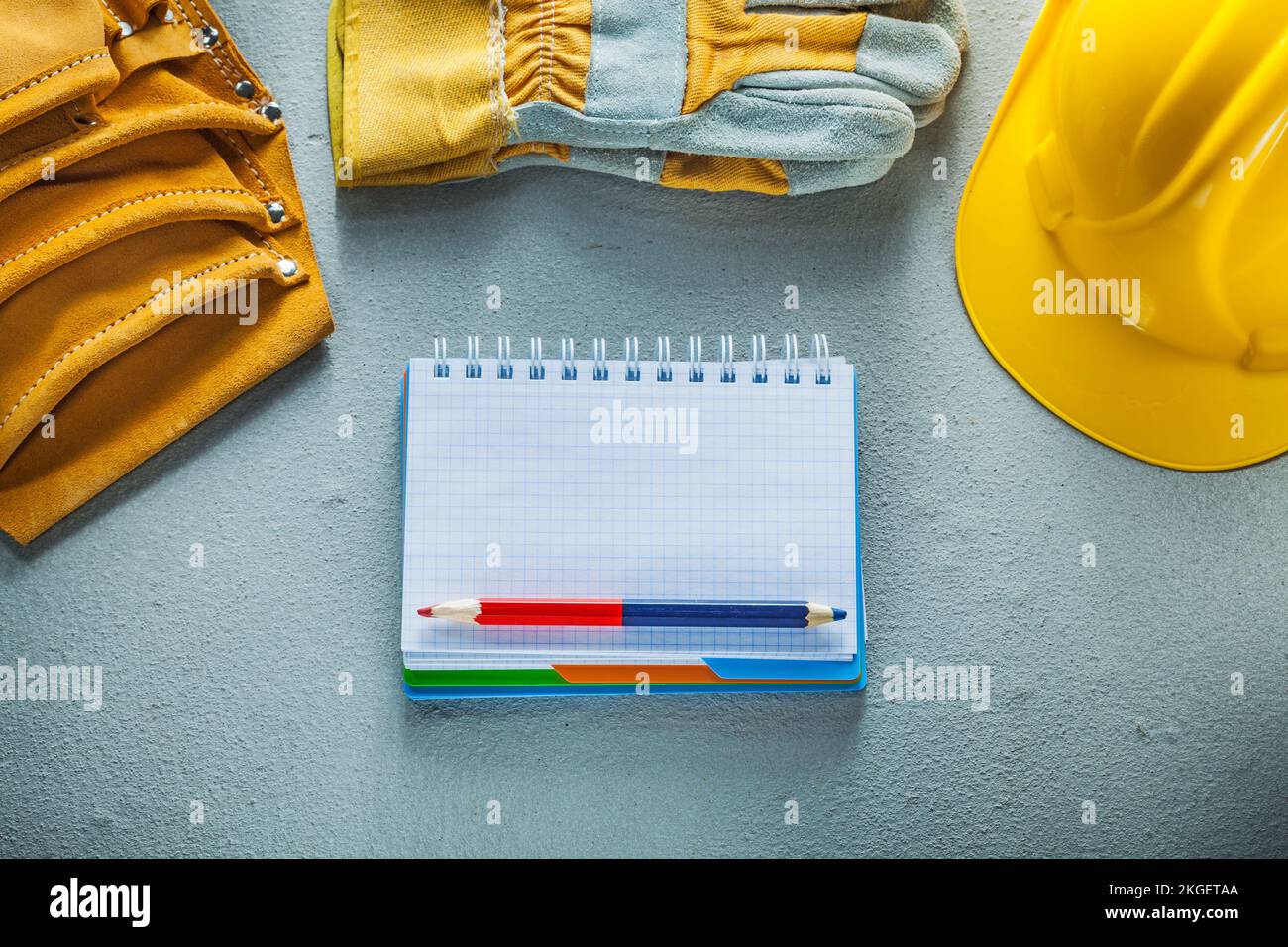 Protective gloves hard hat notepad pencil tool belt on concrete ...
