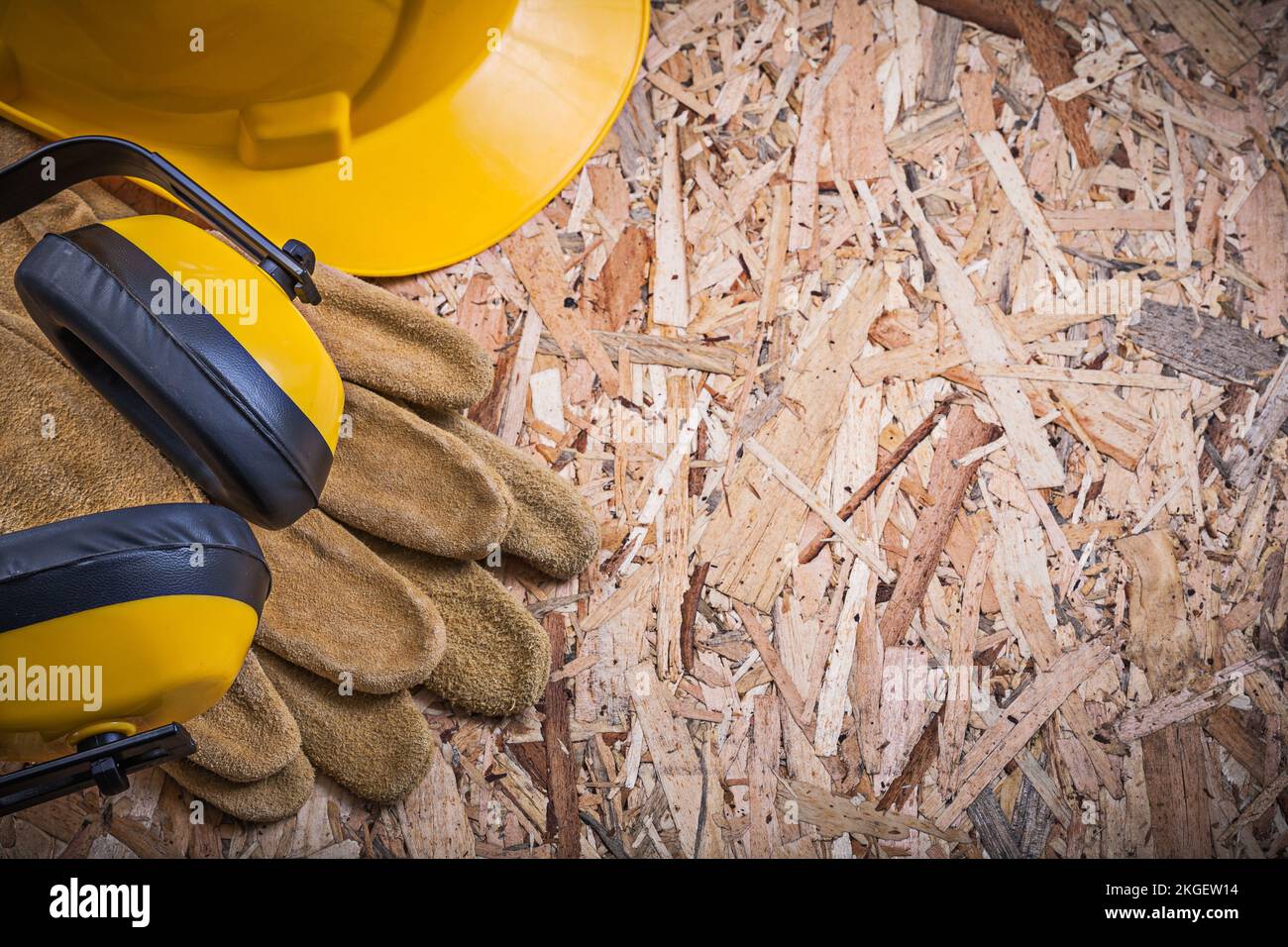 Protective leather gloves hard hat earmuffs on OSB Stock Photo - Alamy