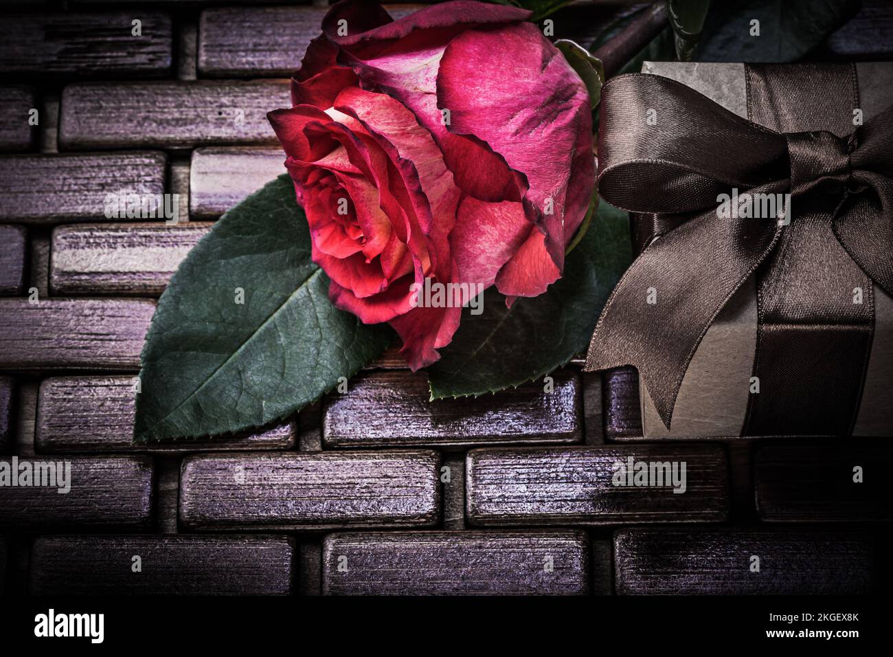 Red expanded rose giftbox on wicker wooden place mat Stock Photo - Alamy