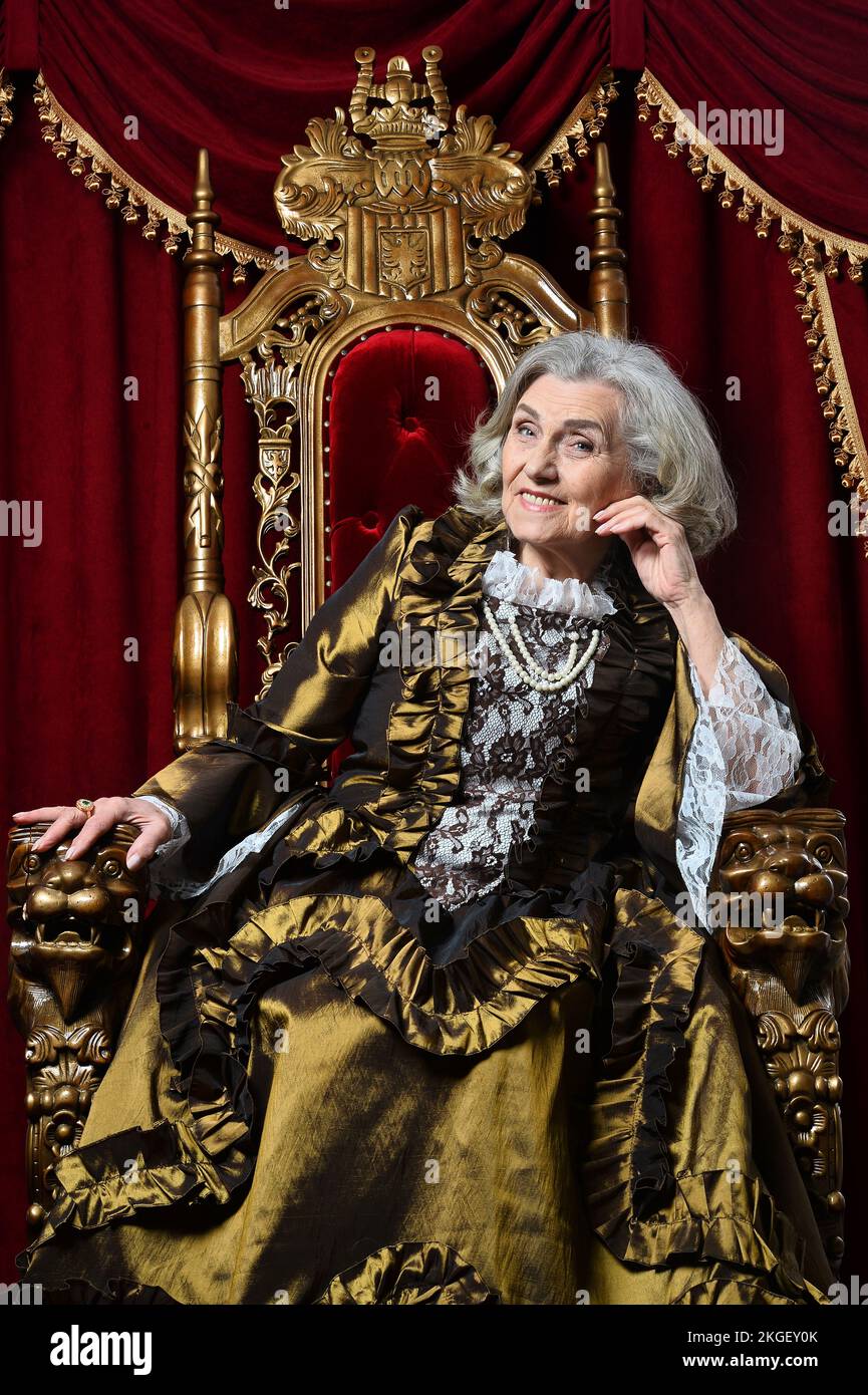 senior queen in a dress sits on a throne Stock Photo - Alamy