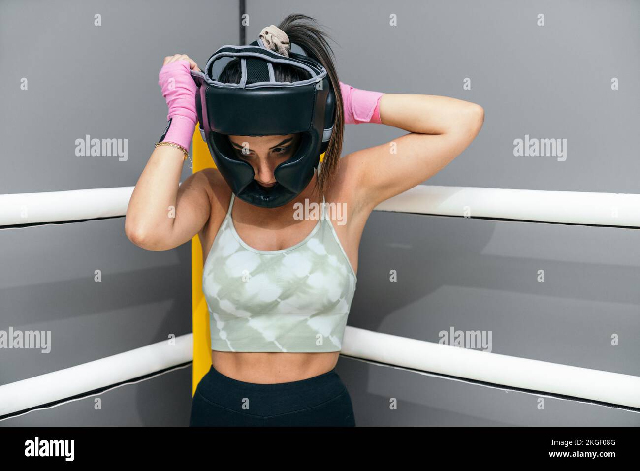 Woman putting protective headgear for practicing kickboxing standing in ...