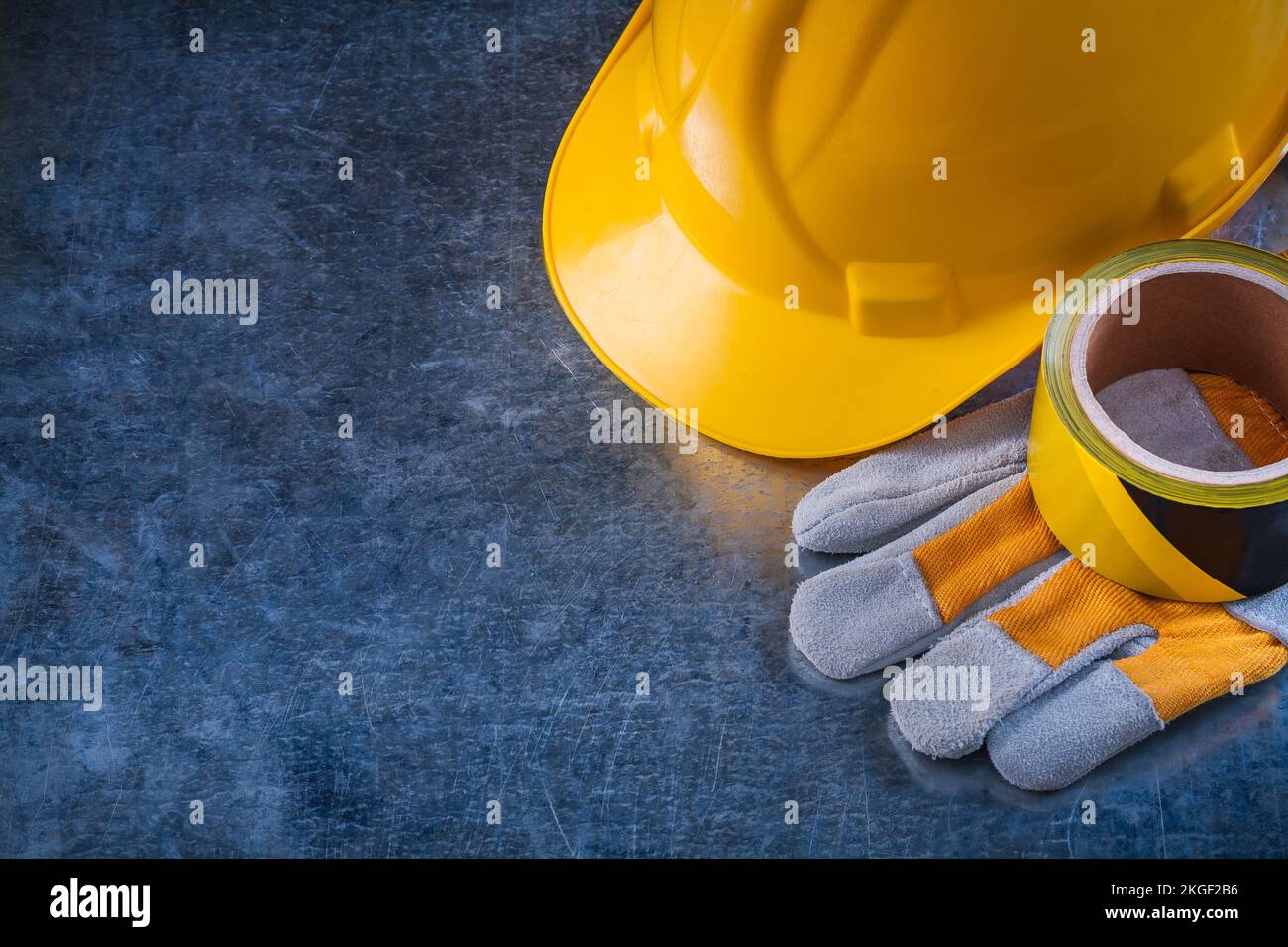 Safety tape hard hat and protective gloves on scratched metallic ...