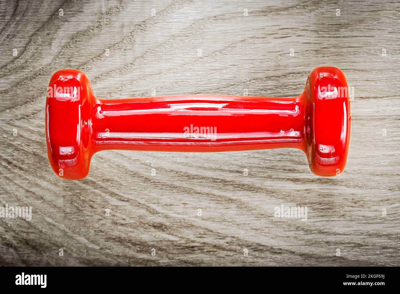 Single red dumbbell weight on wooden board sports training concept ...