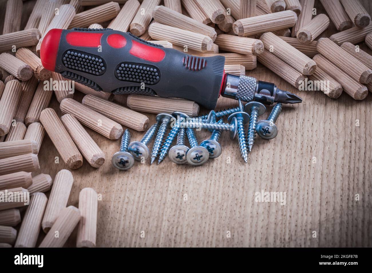 Stack of wooden dowel pins construction nails and insulated screwdriver ...