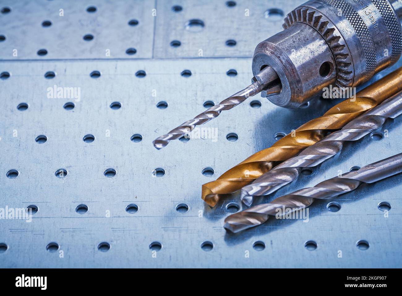 Steel drill with boring bits on perforated metallic background ...