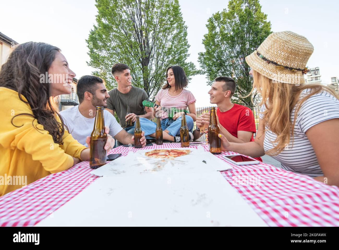 people having fun around a wooden table with take away pizza and ...