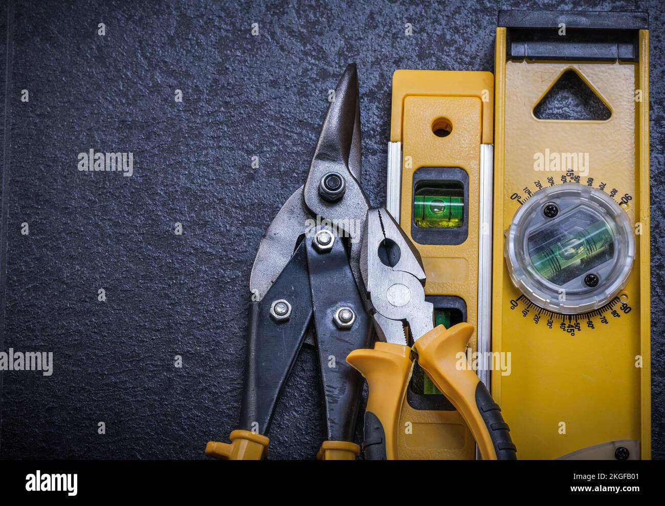 Tin snips gripping tongs construction level on black background Stock ...