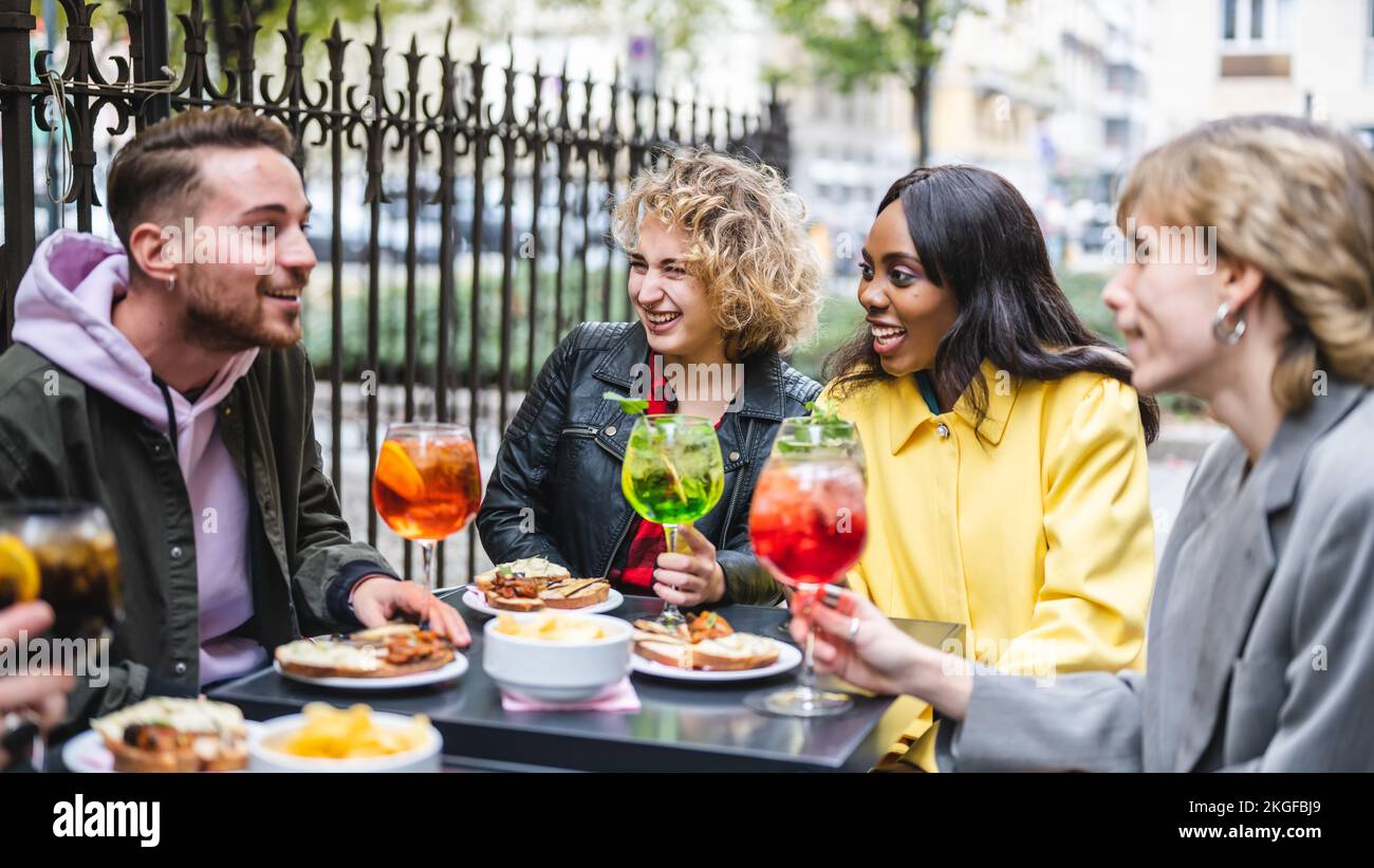 Multiracial happy young friends eating and drinking, diverse cheerful ...
